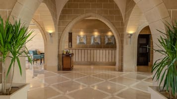Um hall com tetos em arco, uma mesa de recepção e obras de arte emolduradas na parede.