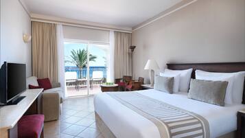 Quarto de hotel com cama, mesa de trabalho com televisão, cadeira, mesa e vista para o exterior.