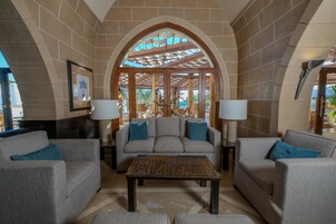 Um hall com sofá, poltronas, mesa de centro e teto com arco de madeira.