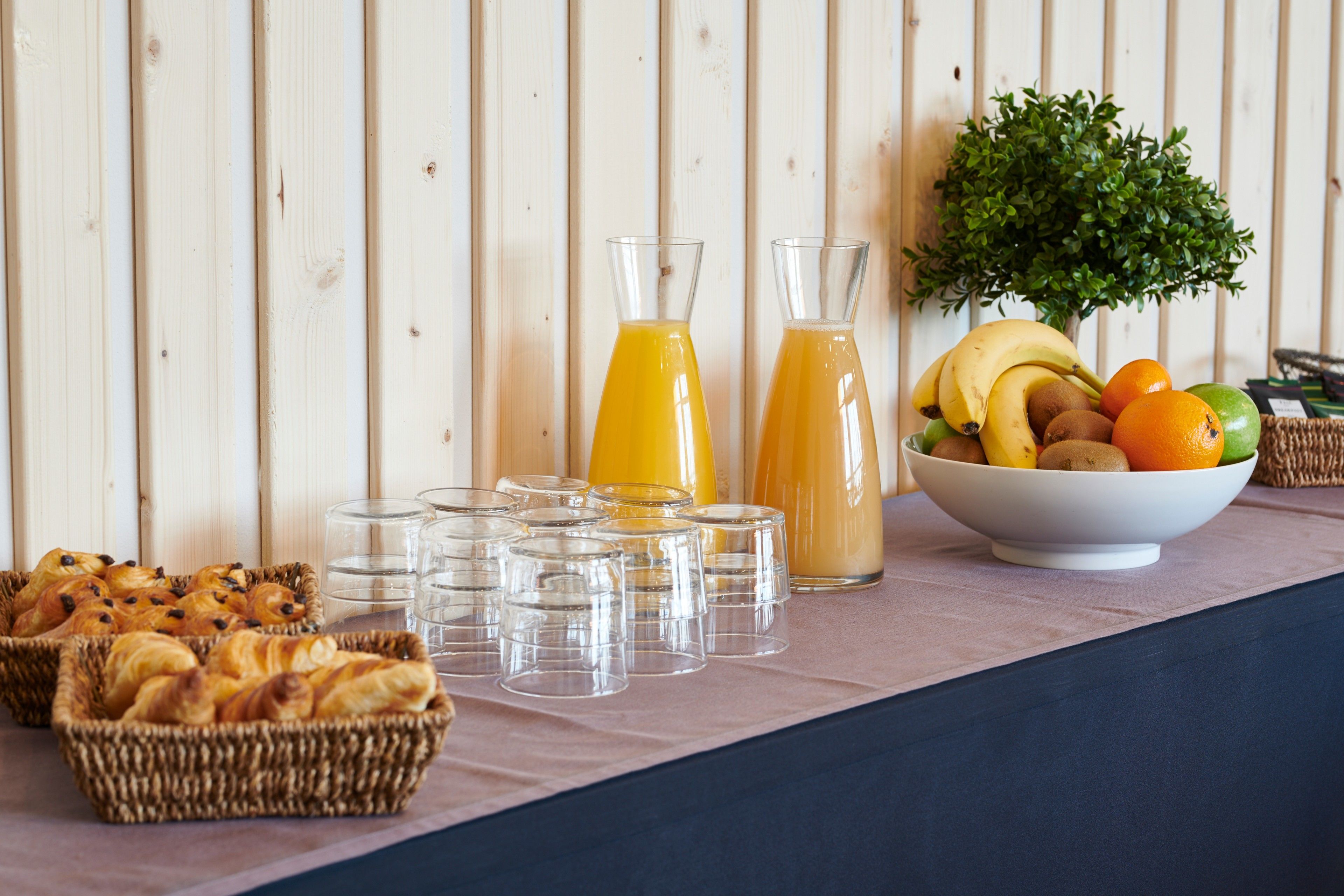 Um buffet de café da manhã com croissants, suco e uma saladeira de frutas.