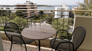 Varanda com mesa redonda e duas cadeiras, com vista para a água e edifícios.