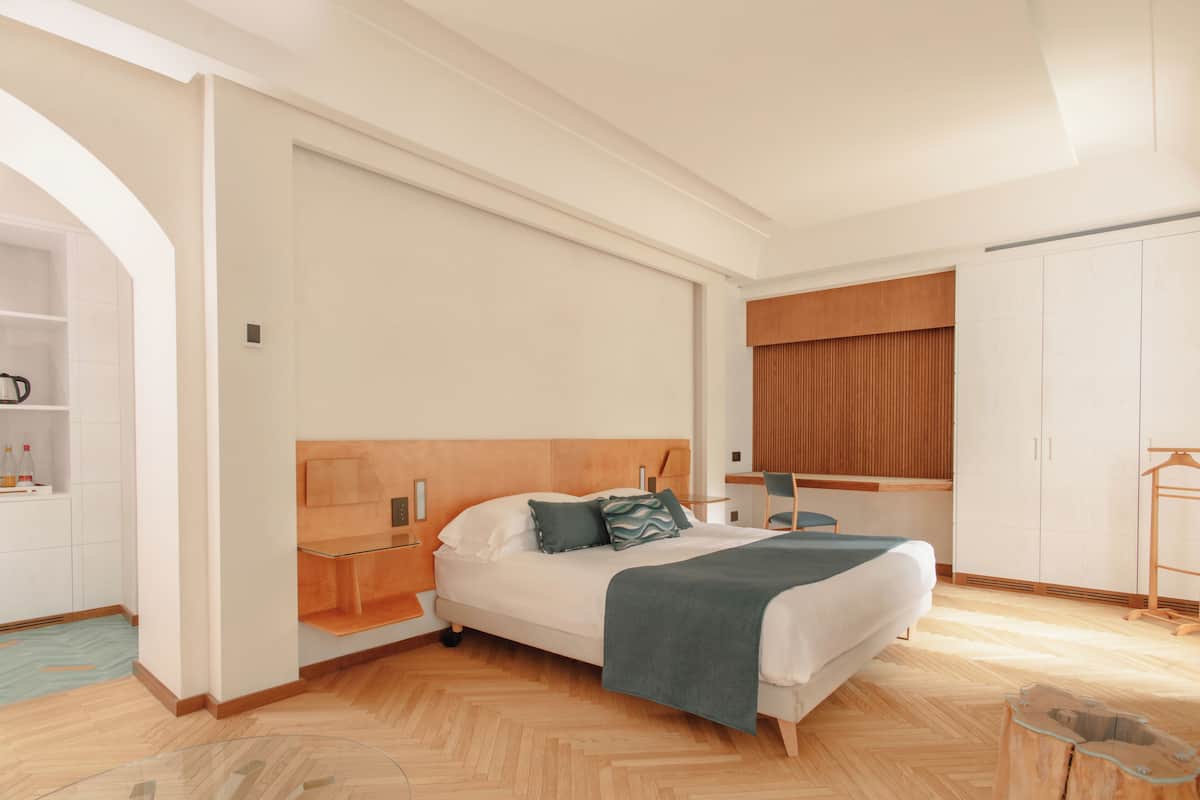 Quarto de hotel moderno com cama, mesa de cabeceira e guarda-roupa.