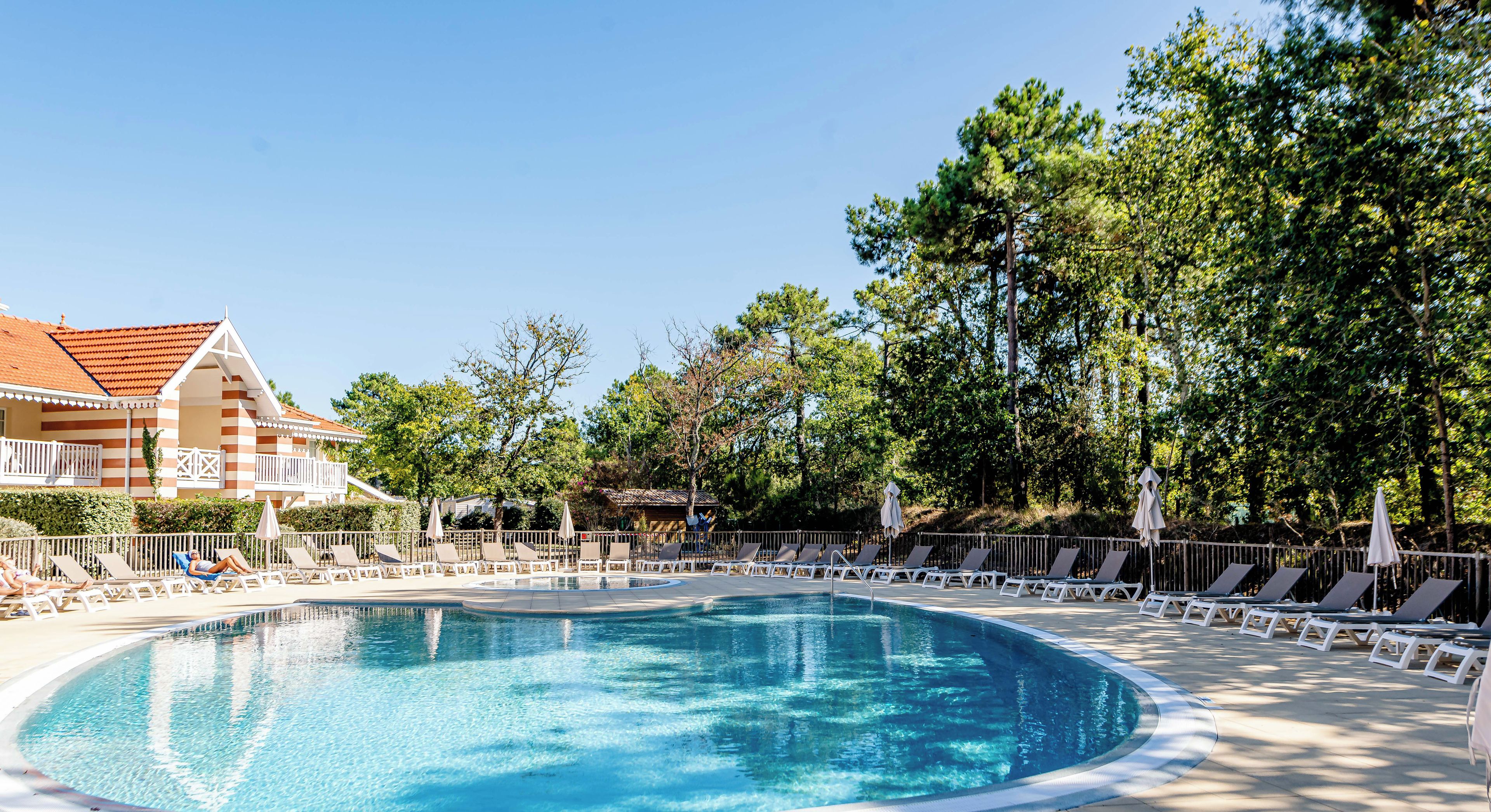 Piscina com espreguiçadeiras e um edifício com telhado telhado.