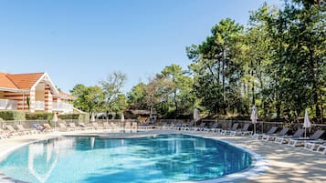 Piscina com espreguiçadeiras e um edifício com telhado telhado.
