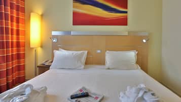 Quarto de hotel com uma cama, um quadro, um abajur e um telefone.