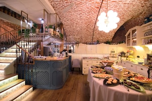 Um interior com vários níveis, incluindo uma escada, um buffet com diversas opções de comida e teto de madeira.