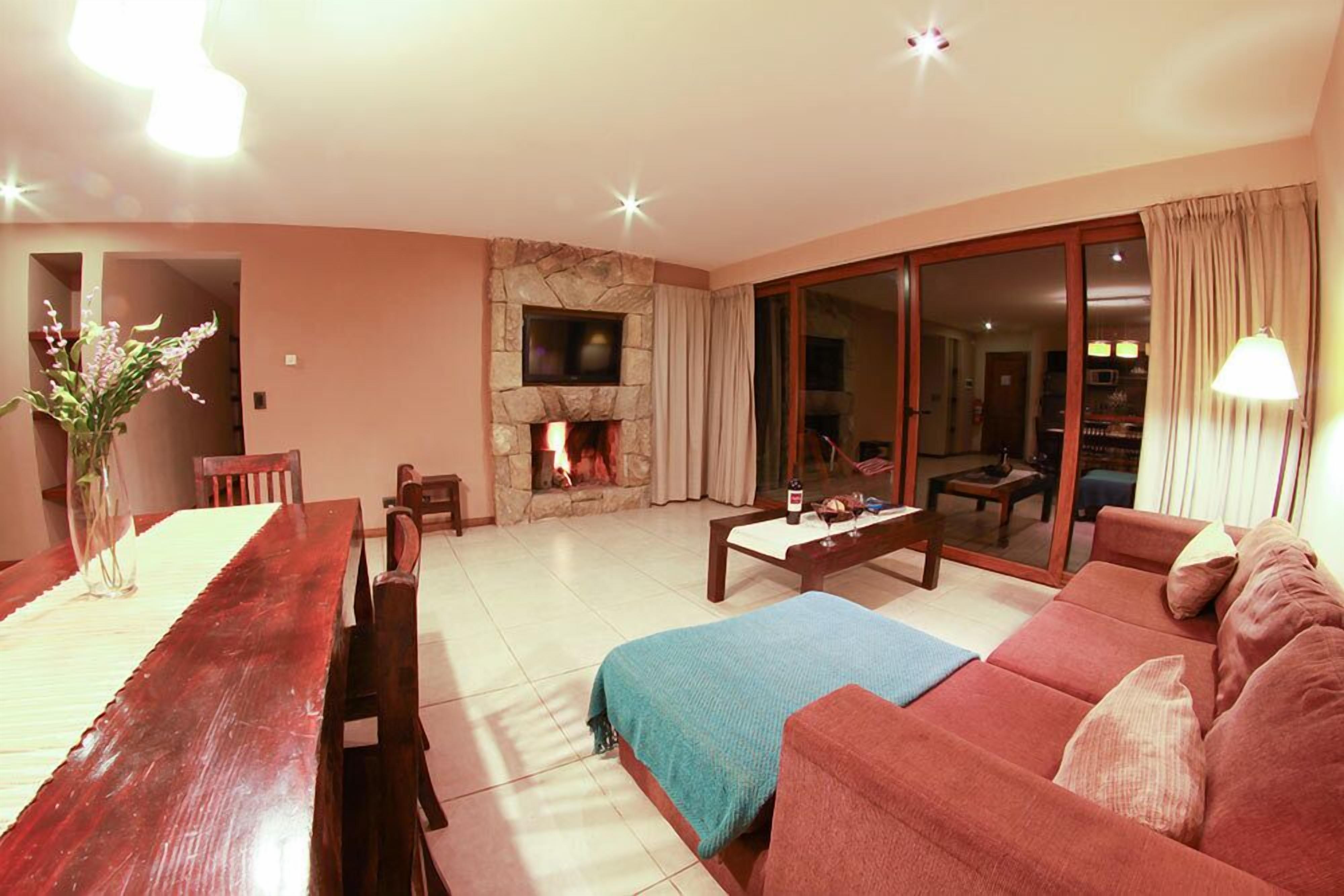 Uma sala de estar com lareira, sofá, mesa de jantar e televisão.