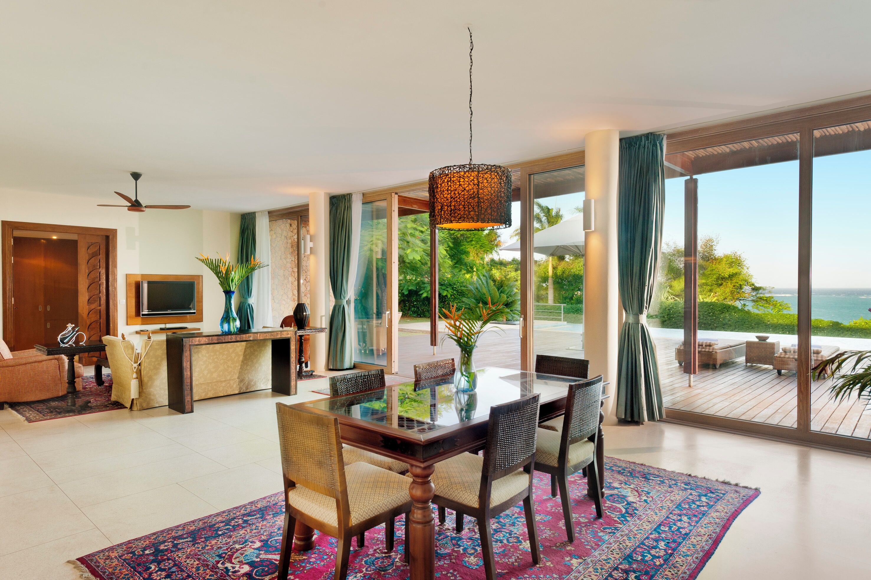 Ampla sala de estar com mesa de jantar, cadeiras, televisão e uma grande janela com vista para o exterior.