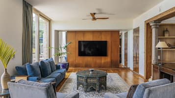 Uma sala de estar ampla, com uma TV grande, assentos confortáveis e um tapete decorativo.