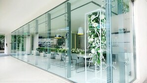 Um edifício moderno com paredes de vidro, área de estar ao ar livre e um arranjo decorativo de plantas.