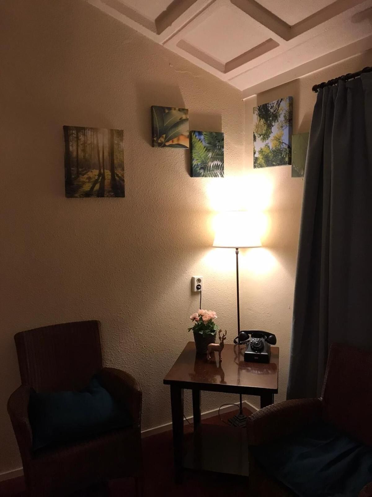 Um quarto acolhedor com teto de madeira, uma mesinha com luminária, telefone e uma cadeira com almofada.