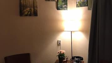 Um quarto acolhedor com teto de madeira, uma mesinha com luminária, telefone e uma cadeira com almofada.