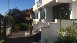 Um edifício com fachada branca, portão e escadaria que leva à entrada.