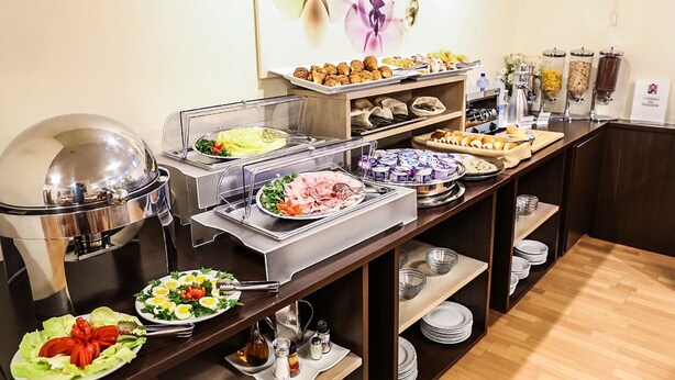 Buffet com diversos alimentos, incluindo saladas, carnes e doces.