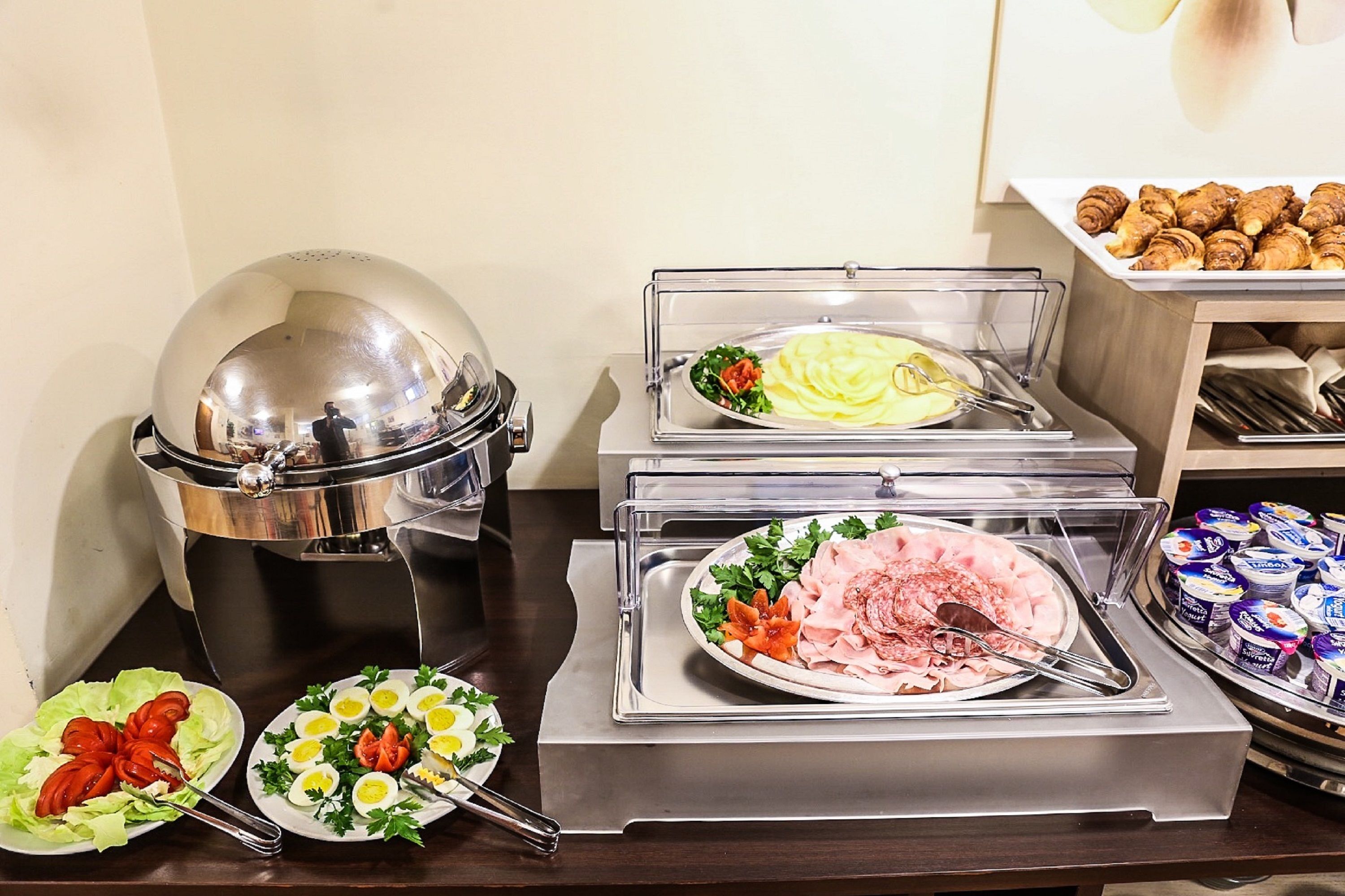 Uma mesa de buffet com diversos alimentos, incluindo saladas, ovos e carne.