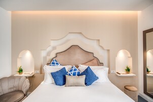 Quarto bem arrumado com uma cama grande, mesas de cabeceira, uma cadeira e um espelho.