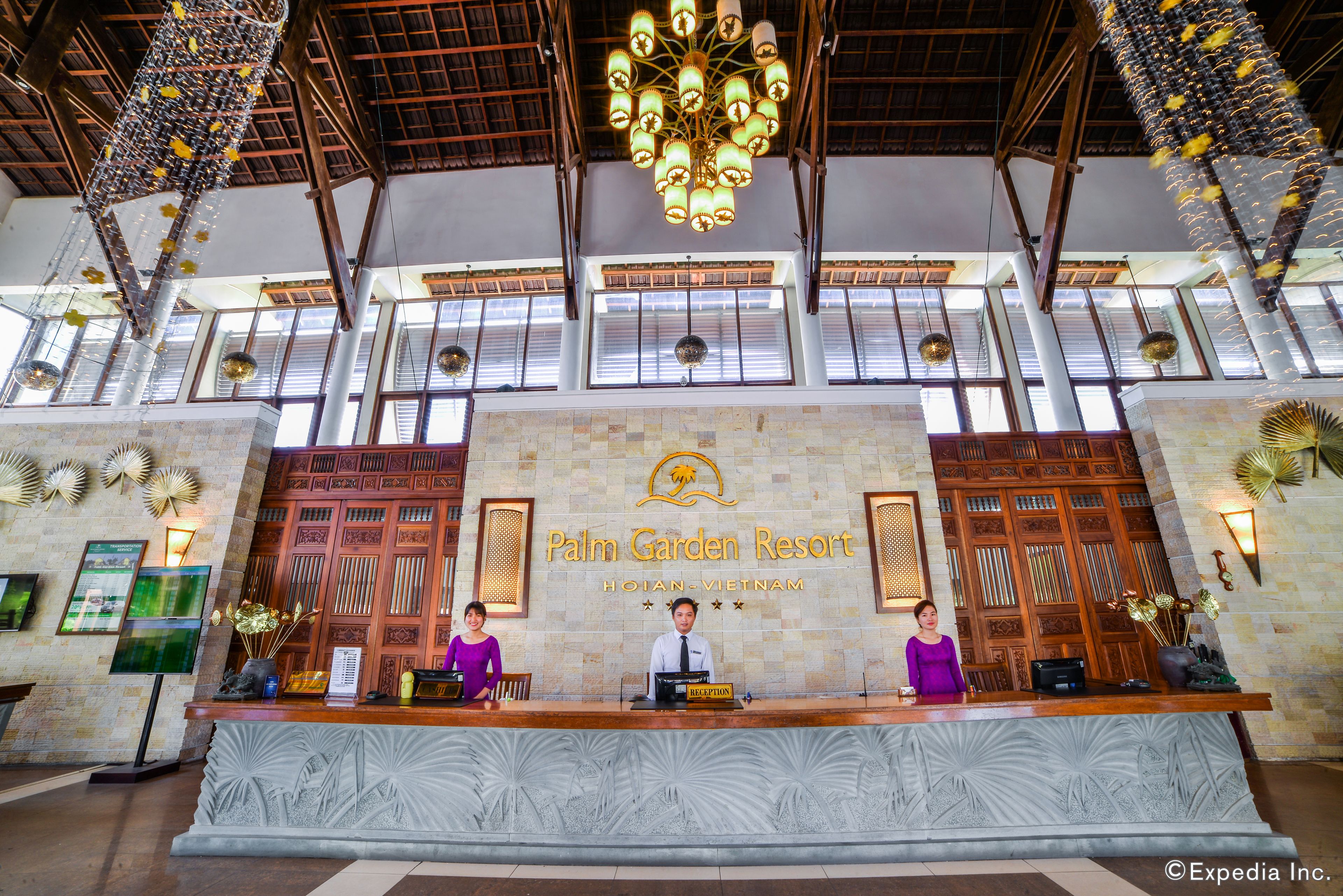 Bancada de recepção no Palm Garden Resort, com fachada de madeira, janelas amplas e um candelabro.