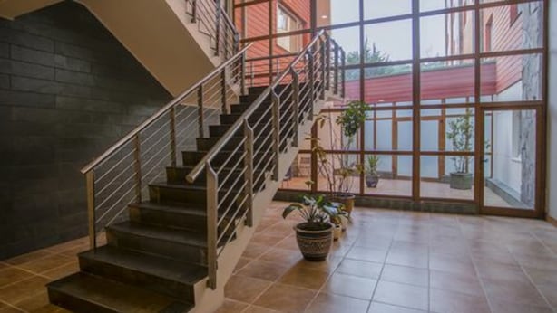 Escadaria com grades de metal que leva a uma varanda com grandes janelas.