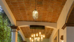 Restaurante com teto de tijolos, luminárias pendentes e chão de azulejos com padrão geométrico.