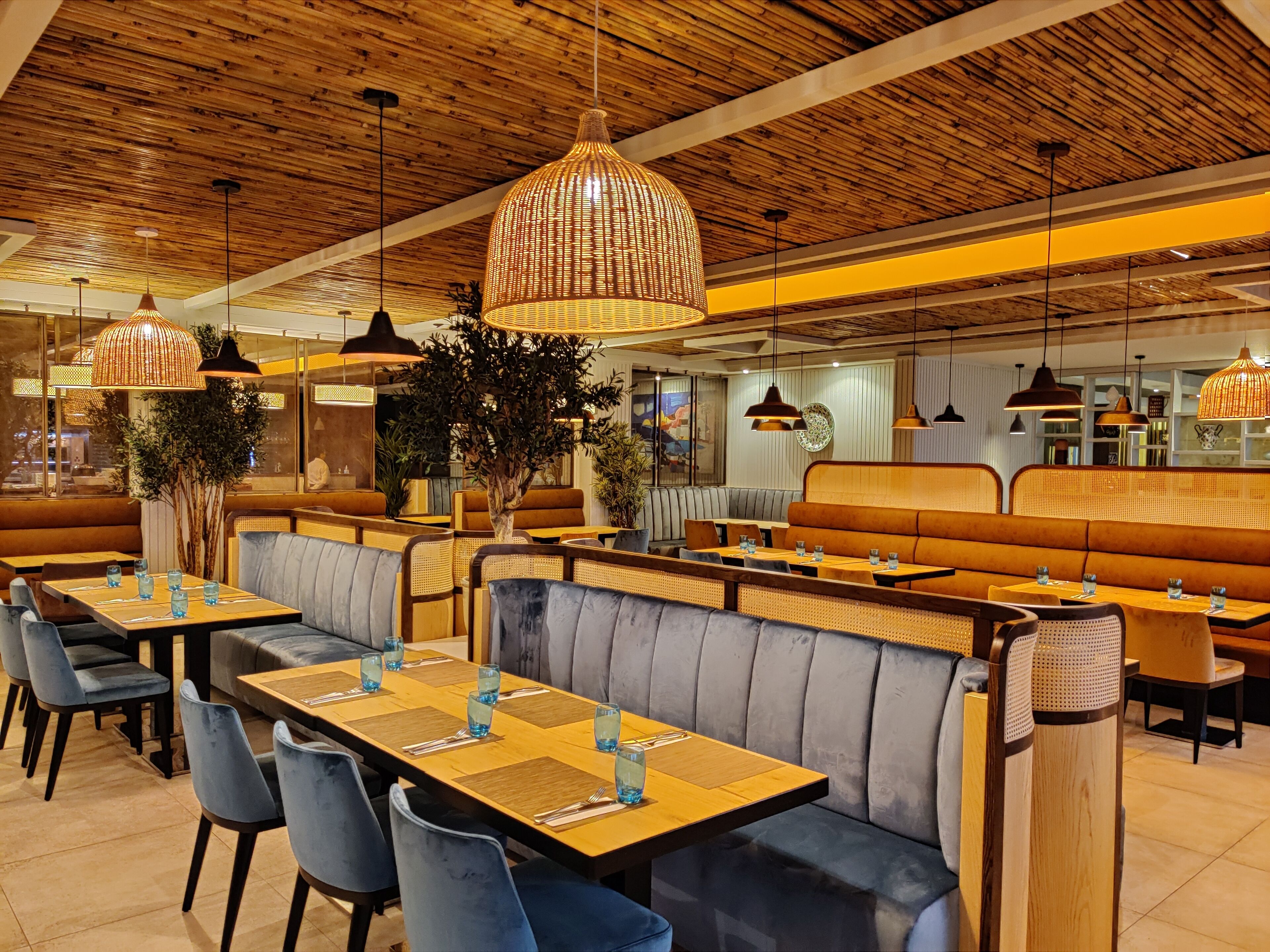 Restaurante com teto de madeira, assentos acolchoados e luminárias pendentes.