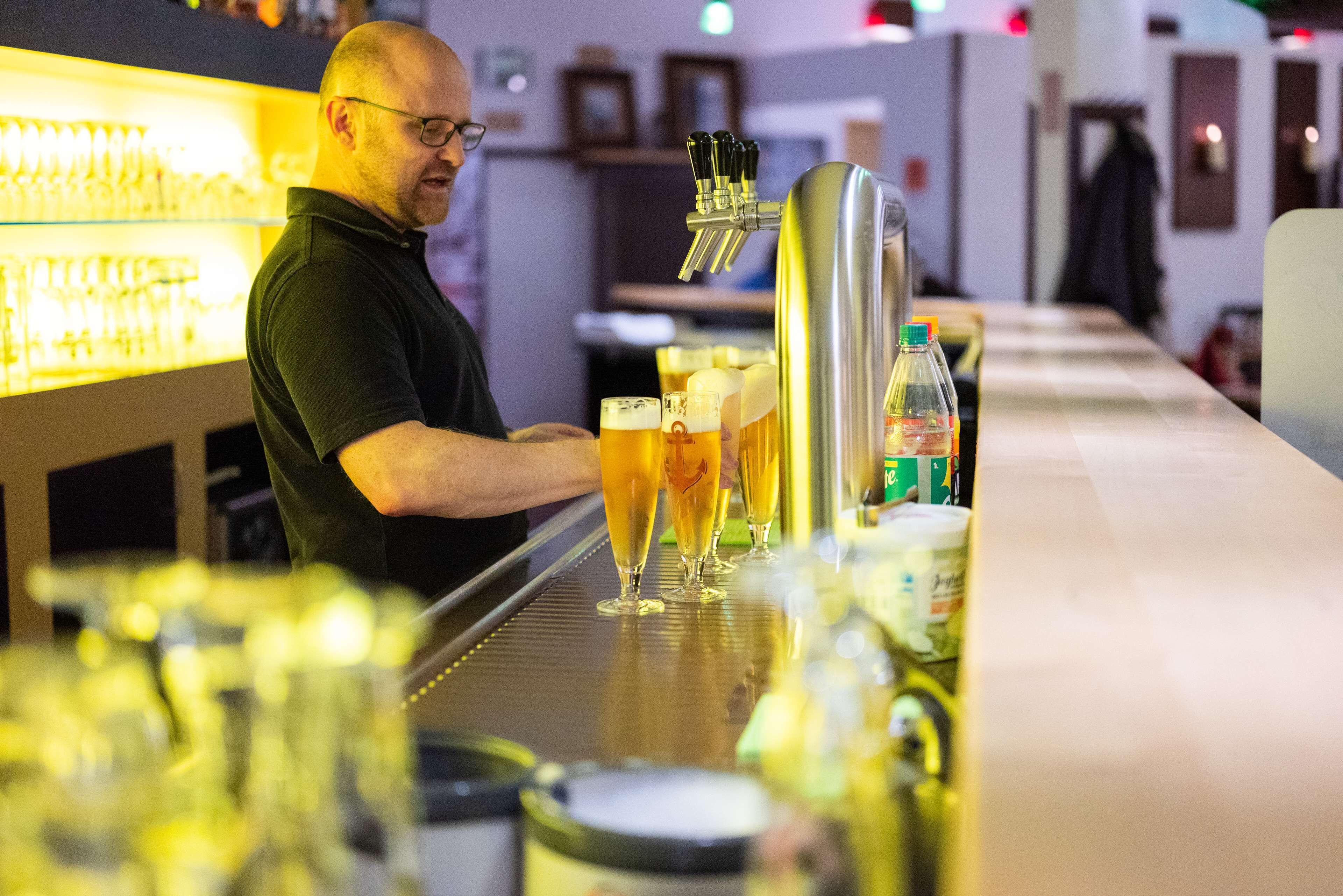 Uma área de bar com um bartender servindo bebidas de uma torneira.
