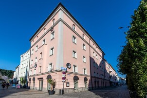 Um edifício rosa com vários andares, um relógio e uma placa que indica um restaurante.
