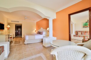 Quarto de hotel com cama, escrivaninha, cadeira, mesa redonda e sofá.