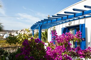 Um edifício branco com persianas azuis e uma pérgula azul.