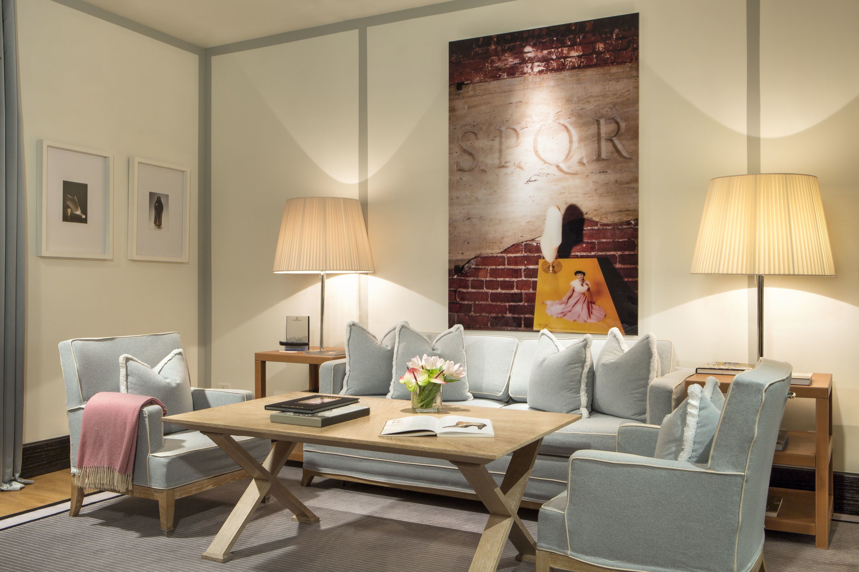 Uma sala de estar moderna com um conjunto de sofá, uma mesa de centro e duas luminárias. Há quadros nas paredes e um pôster grande.