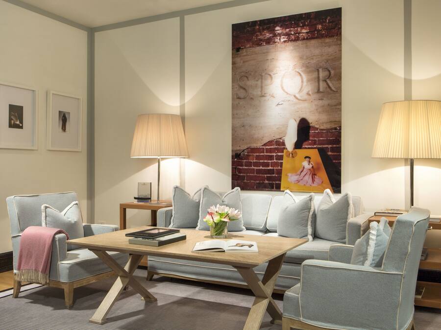 Uma sala de estar moderna com um conjunto de sofá, uma mesa de centro e duas luminárias. Há quadros nas paredes e um pôster grande.