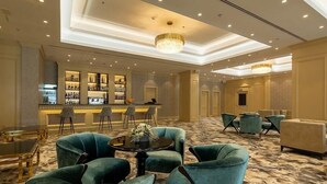 Um saguão de hotel com área de bar, assentos e um lustre.