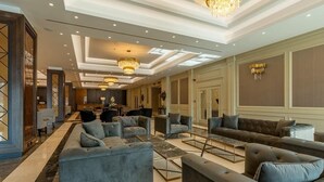 Um hall amplo com assentos modernos, lustres e teto bem iluminado.