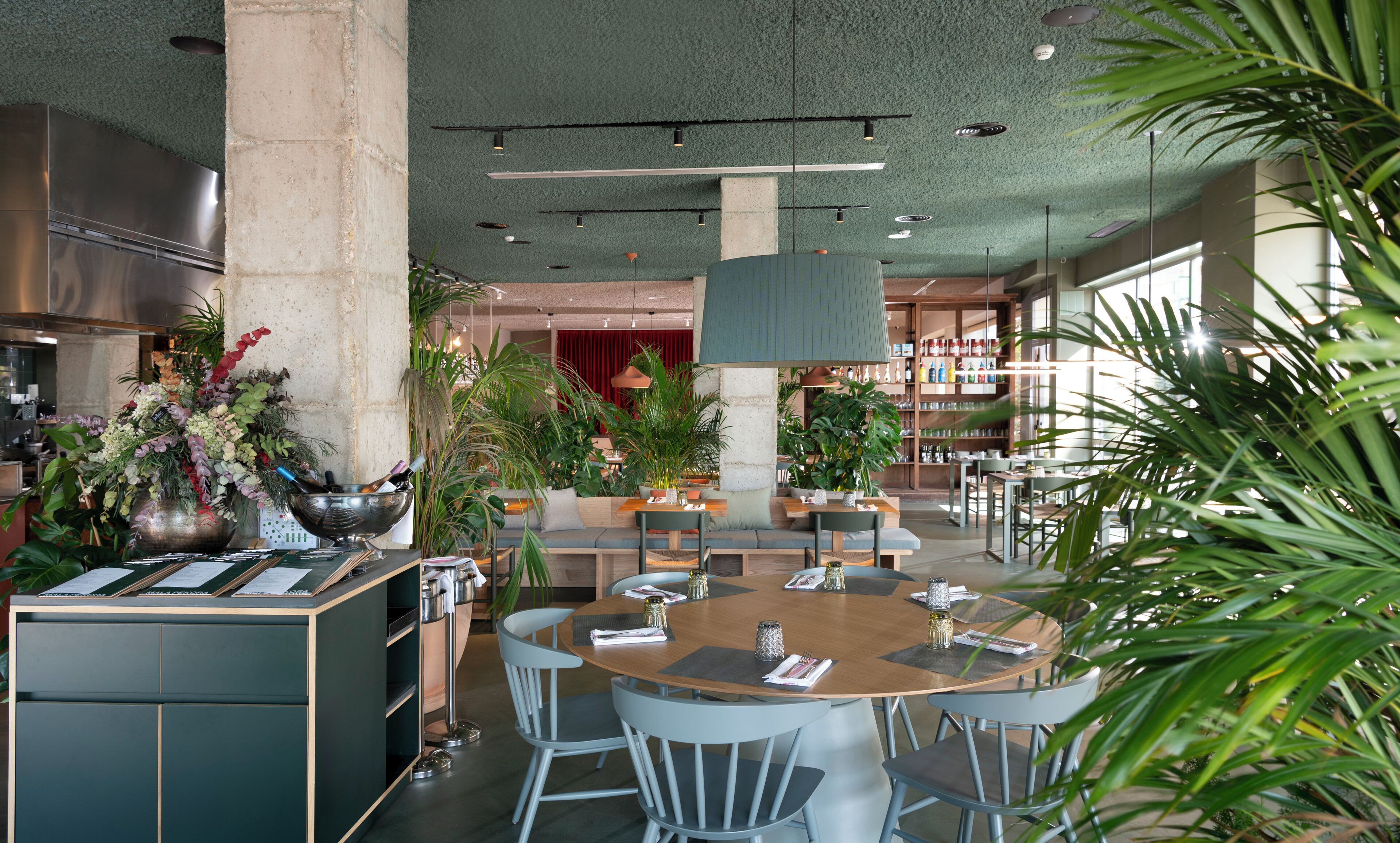 Um restaurante moderno com uma mesa redonda central, assentos e um bar.