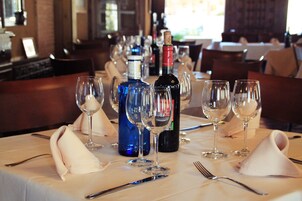 Mesa posta com taças de vinho, uma garrafa e talheres.