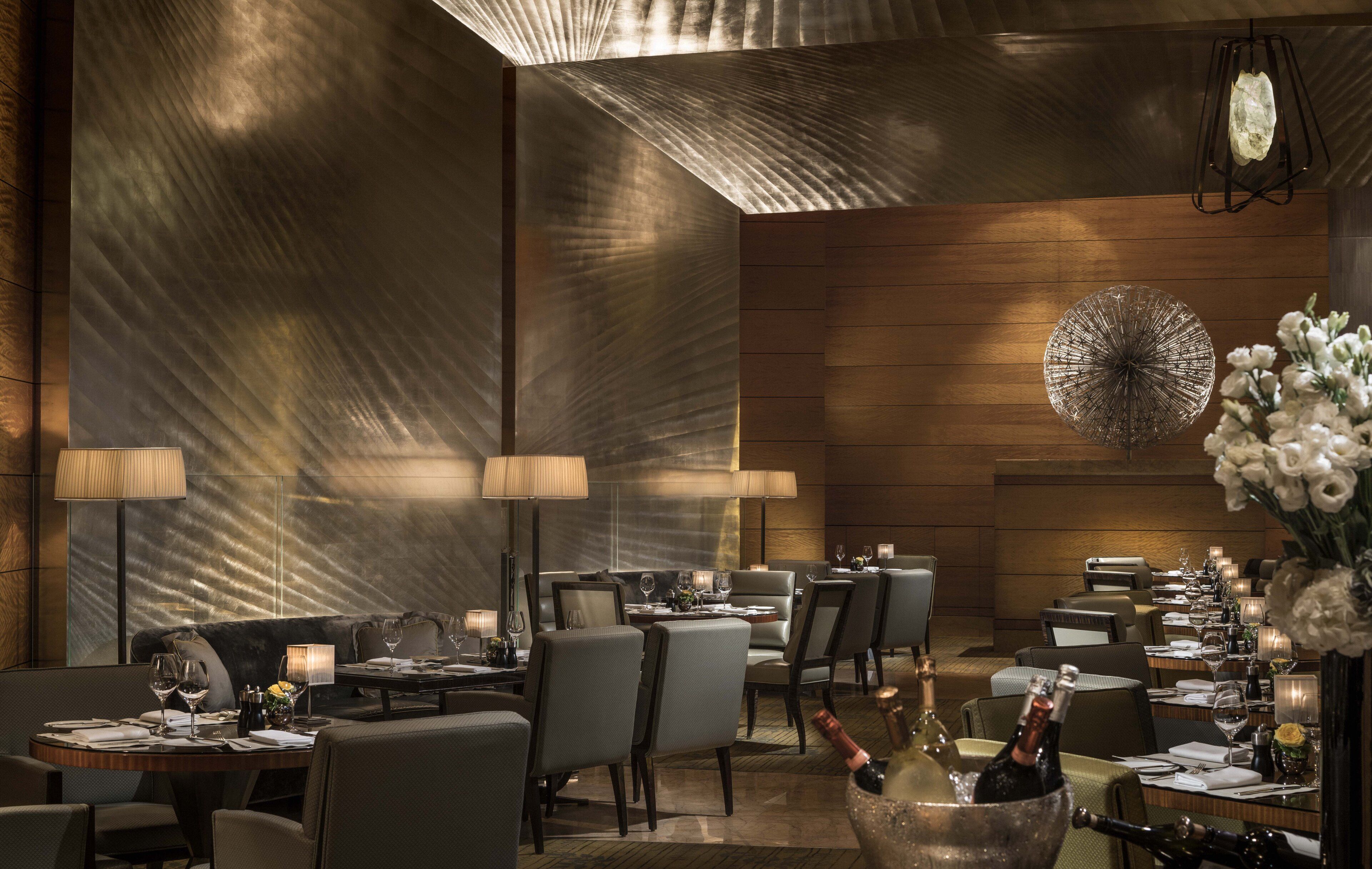 Um interior de restaurante moderno com uma longa mesa de jantar, várias cadeiras e uma peça decorativa central.