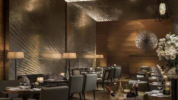 Um interior de restaurante moderno com uma longa mesa de jantar, várias cadeiras e uma peça decorativa central.
