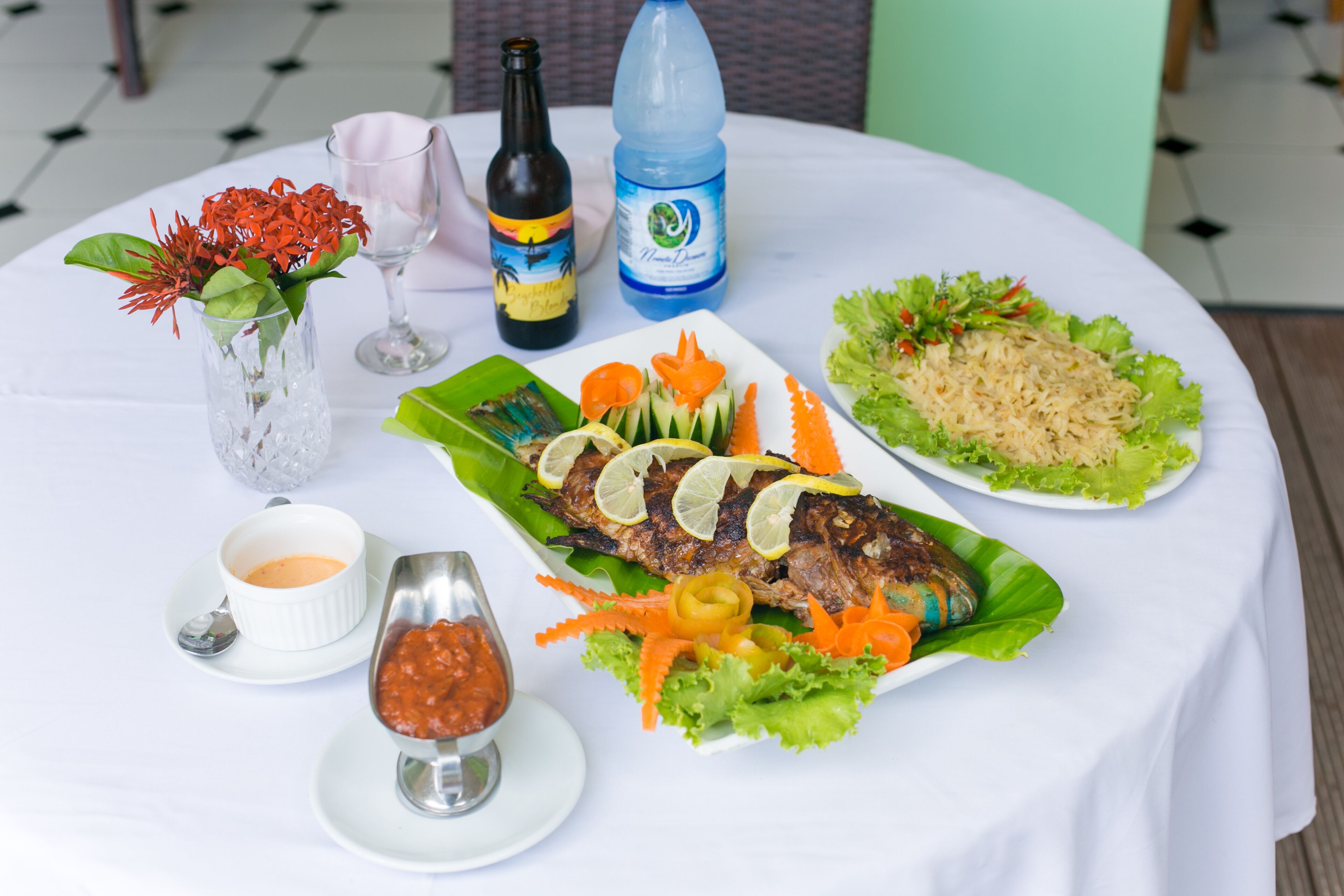 Uma mesa com uma variedade de pratos, incluindo carne grelhada, arroz e legumes, acompanhados de molhos e bebidas.