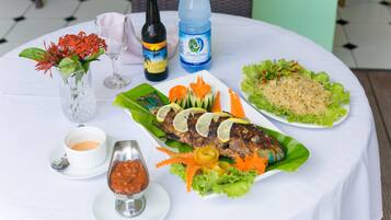 Uma mesa com uma variedade de pratos, incluindo carne grelhada, arroz e legumes, acompanhados de molhos e bebidas.