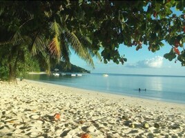 Na praia, praia de areia branca, guarda-sóis de praia, toalhas de praia 