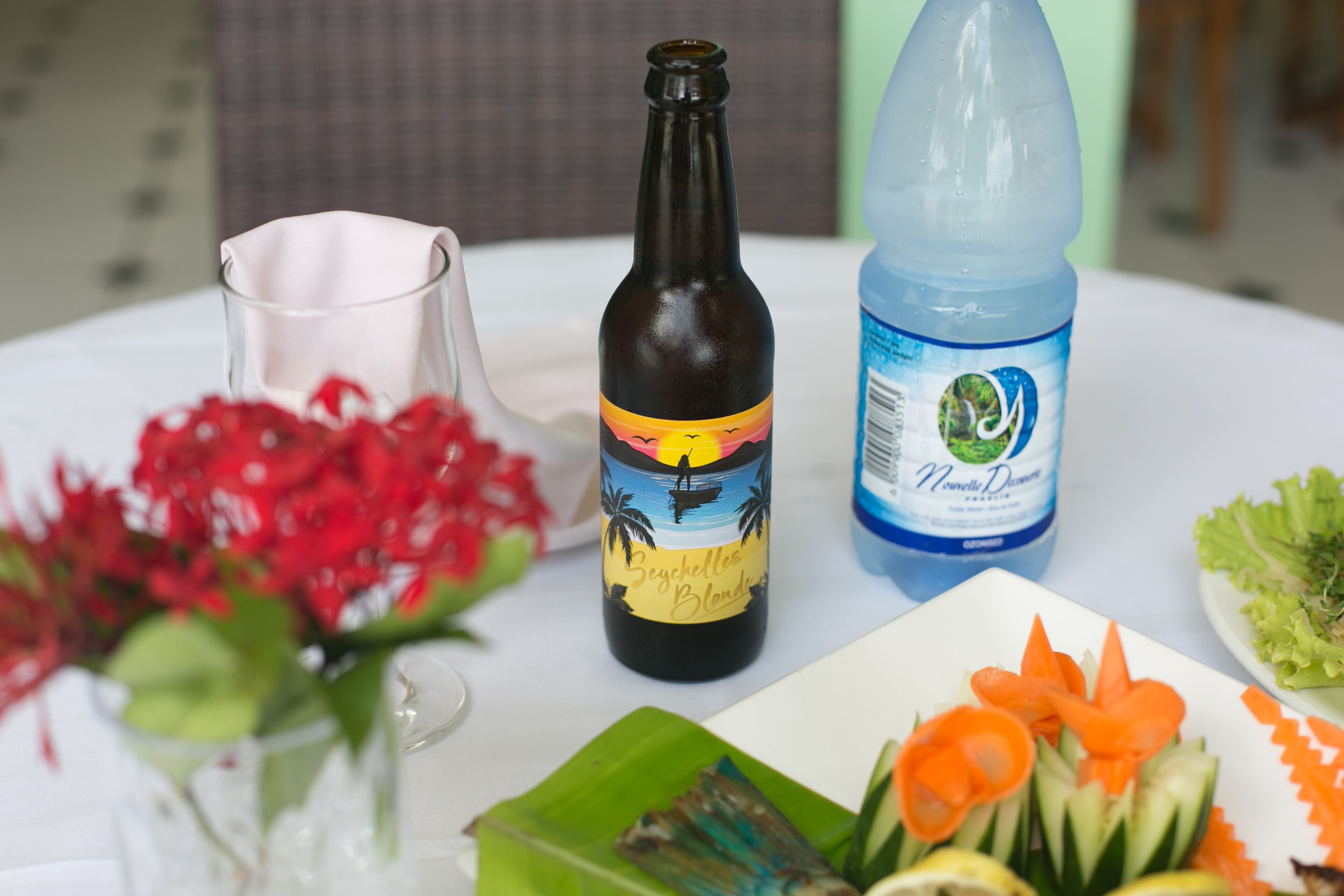 Uma mesa com uma garrafa de cerveja, uma garrafa de água, um copo e um prato de comida.
