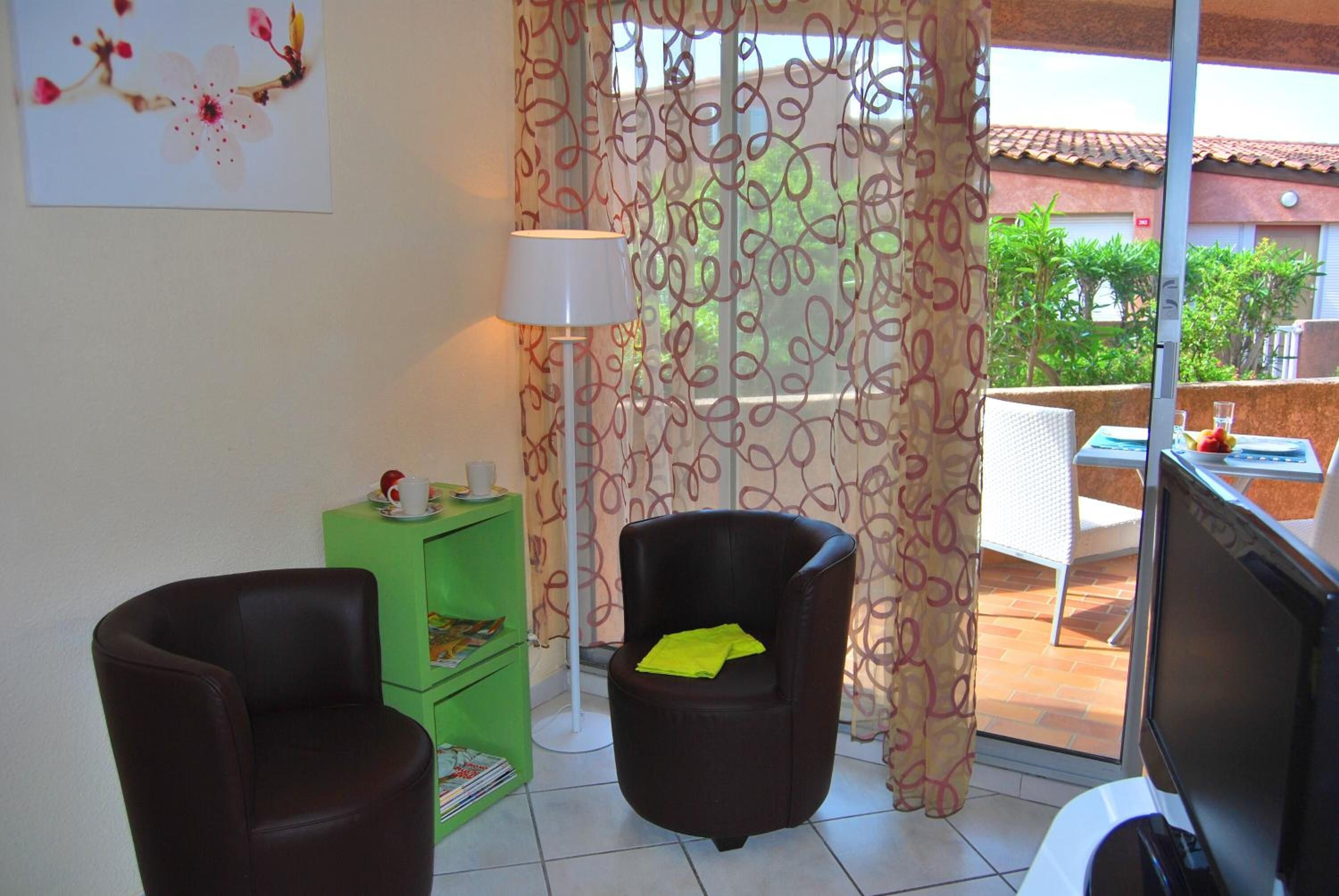 Quarto com sofá, cadeira, televisão e mesa com um copo.