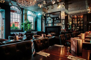 Restaurante com assentos em couro, lareira e estante de livros.