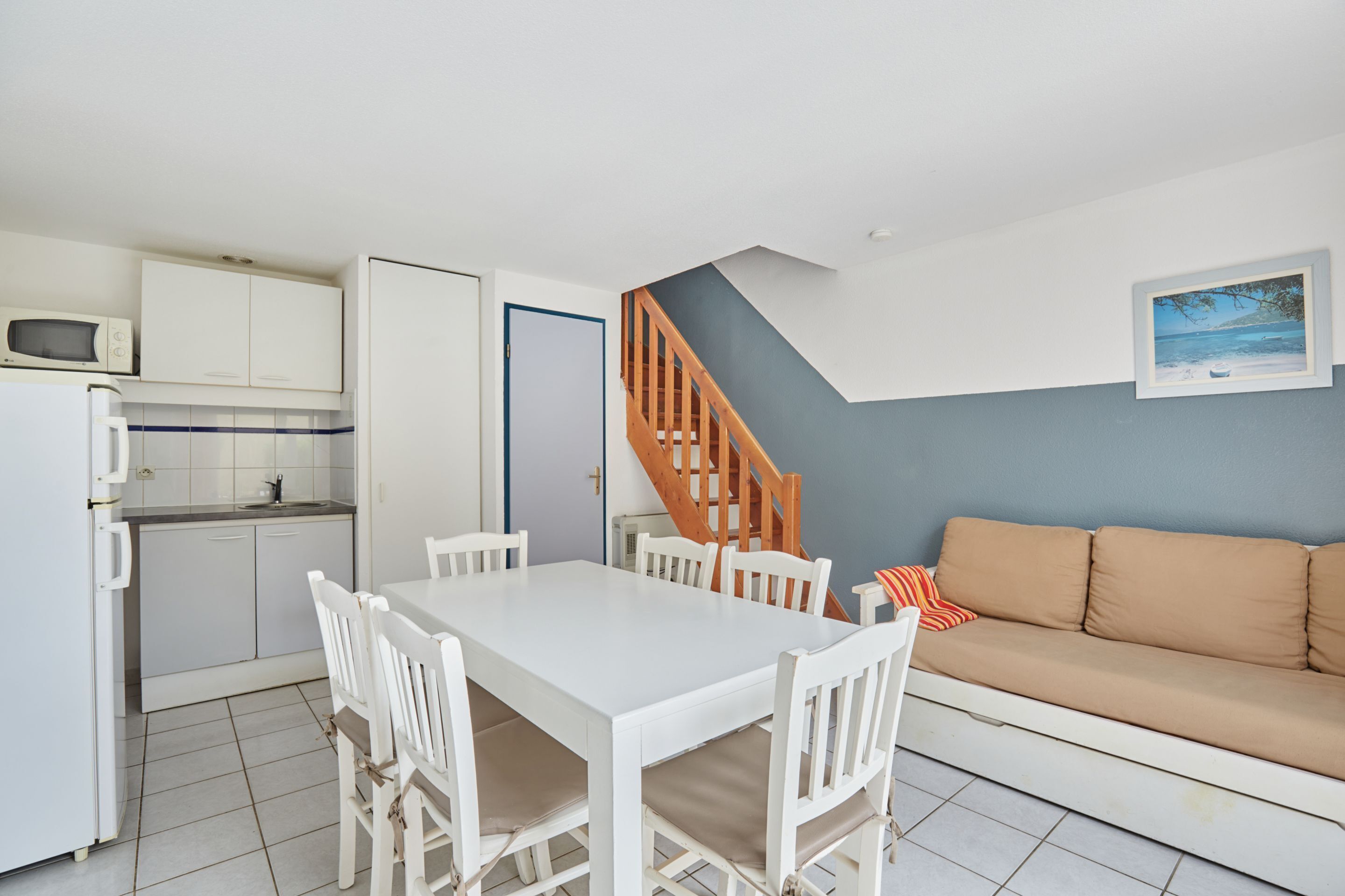 Espaço compacto com cozinha, sala de jantar e sofá.