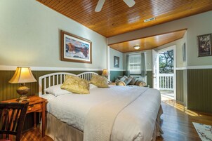 Quarto com cama grande, teto de madeira e vista para o exterior.
