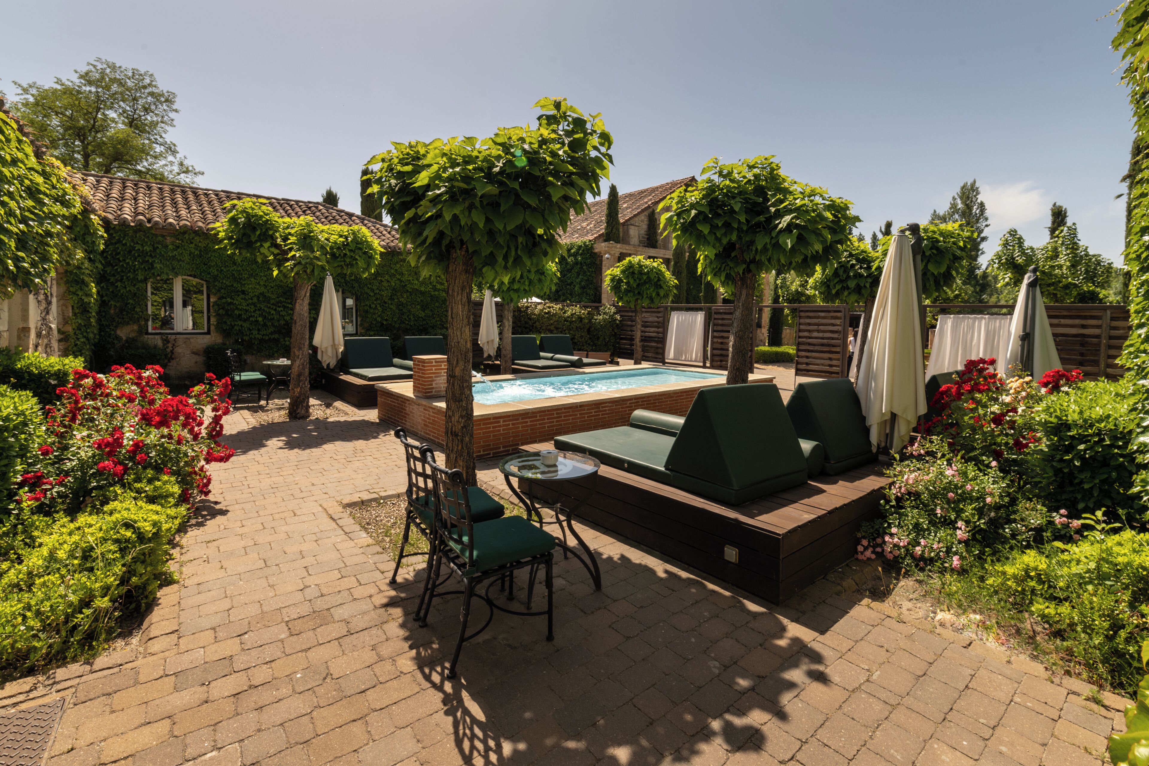 Uma área à beira da piscina com um espaço de estar integrado, uma mesa e cadeiras.