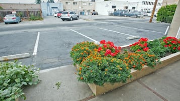 Um estacionamento com vários carros e um canteiro de flores vermelhas e laranja.