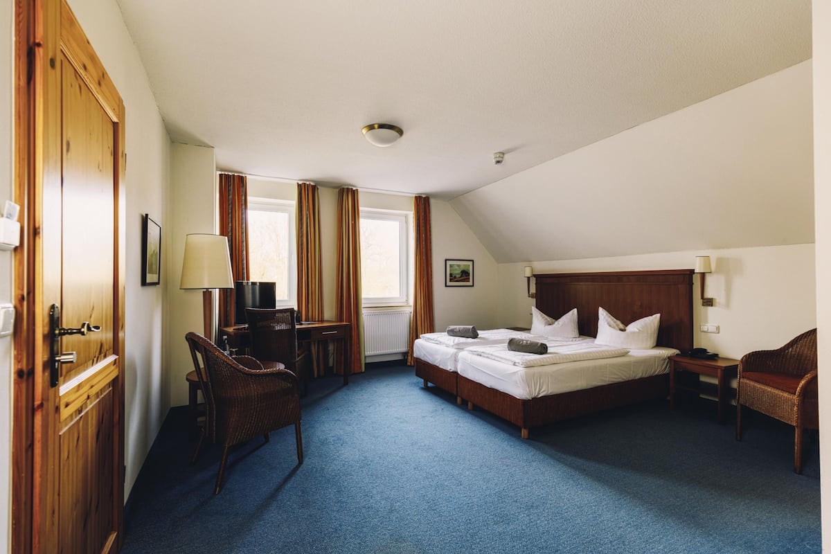 Quarto de hotel com uma cama grande, uma escrivaninha, uma cadeira e uma televisão.