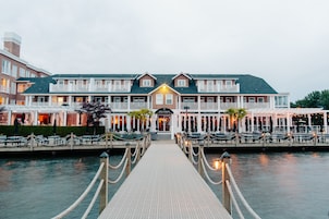 Hotel à beira-mar com entrada central, área de estar ao ar livre e um cais.