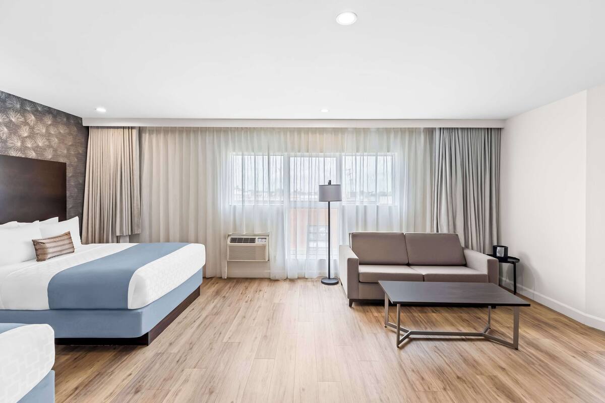 Quarto de hotel com uma cama, um sofá, uma mesa de centro e um abajur.