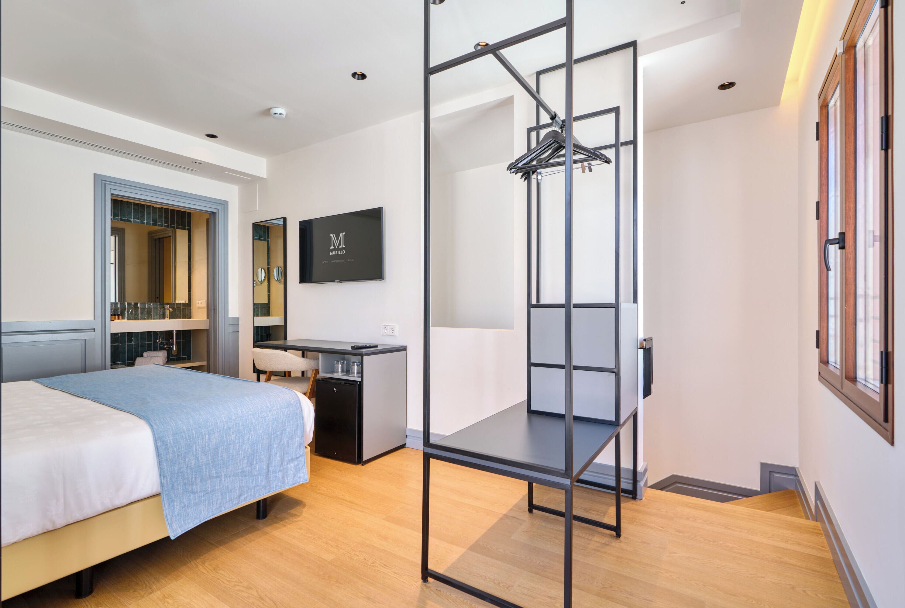 Quarto de hotel moderno com cama, escrivaninha e um espelho grande.